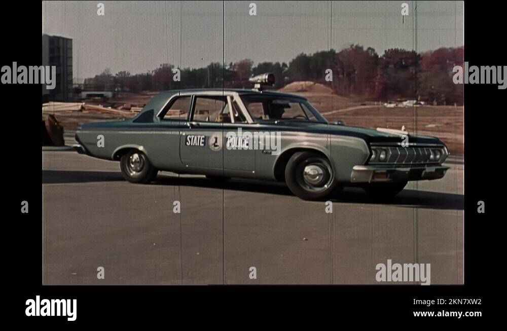 1960s: Police car stops and officers get out and crouch behind it ...