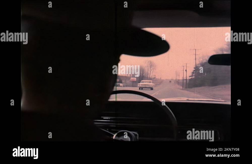 1960s: Agent behind wheel of police car talks on radio. Agent turns on ...
