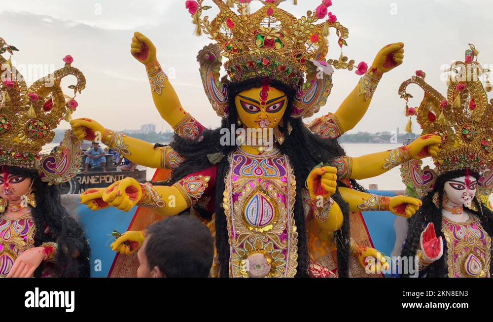 Group of unidentified people submerging a big statue of Hindu goddess ...