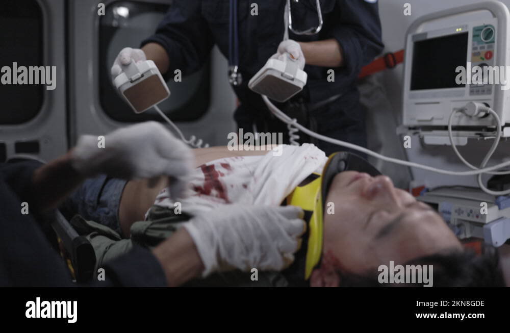 Ambulance crew using defibrillator for unconscious patient Stock Video ...