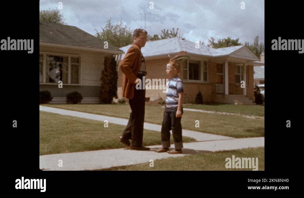 1950s: Boy looks then walks backwards down the sidewalk. Slate. Boy and ...