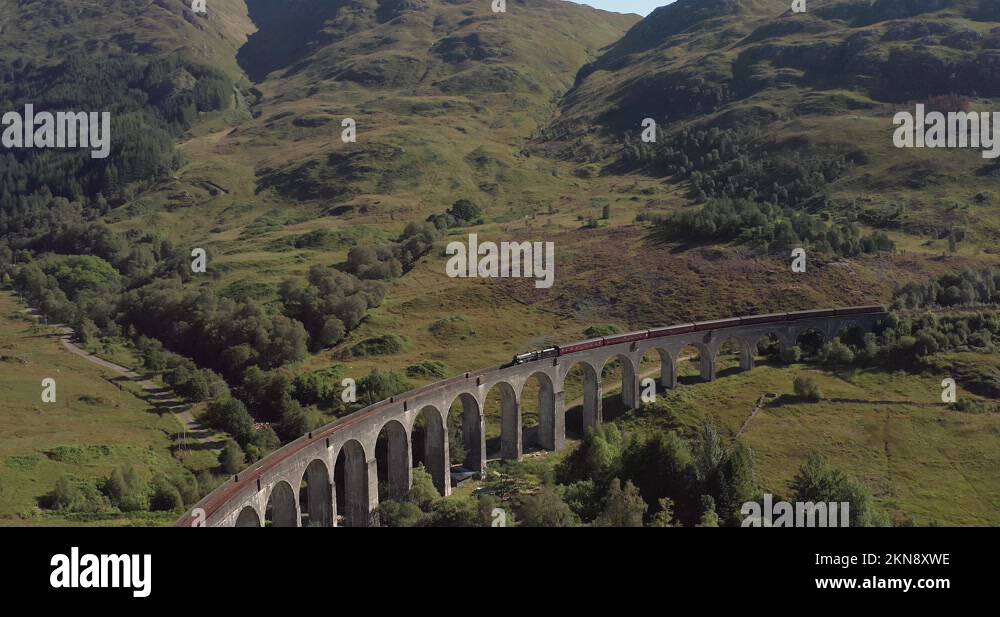 A steam train crosses the Glennfinnan Viaduct in Scotland, recreating a ...