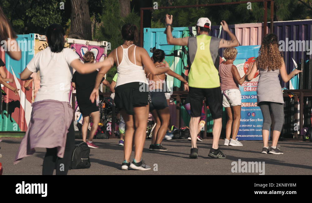 Back view of people taking Zumba class in open air square. Static Stock ...