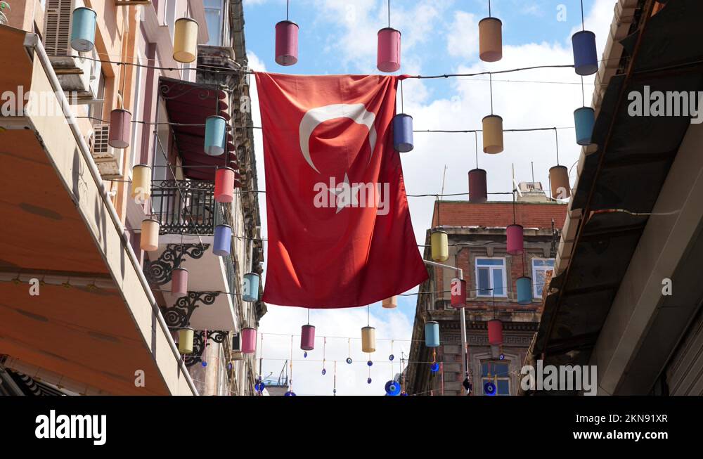 Turkish flag hang down from wire between buildings at Karakoy, lit by ...