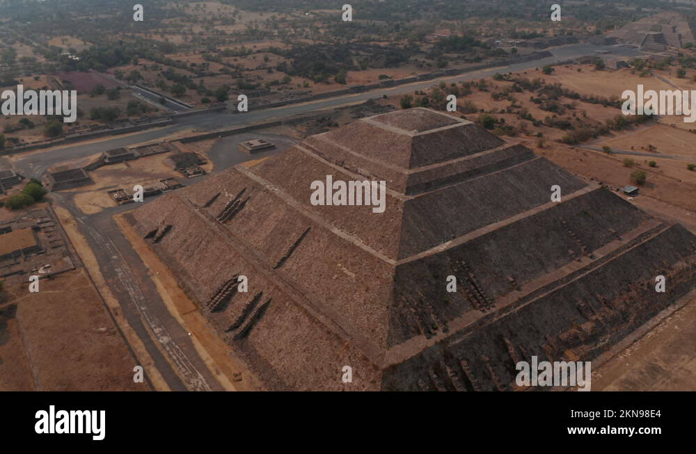 Backwards reveal of ancient huge pyramid. Tilt up to view dry landscape ...