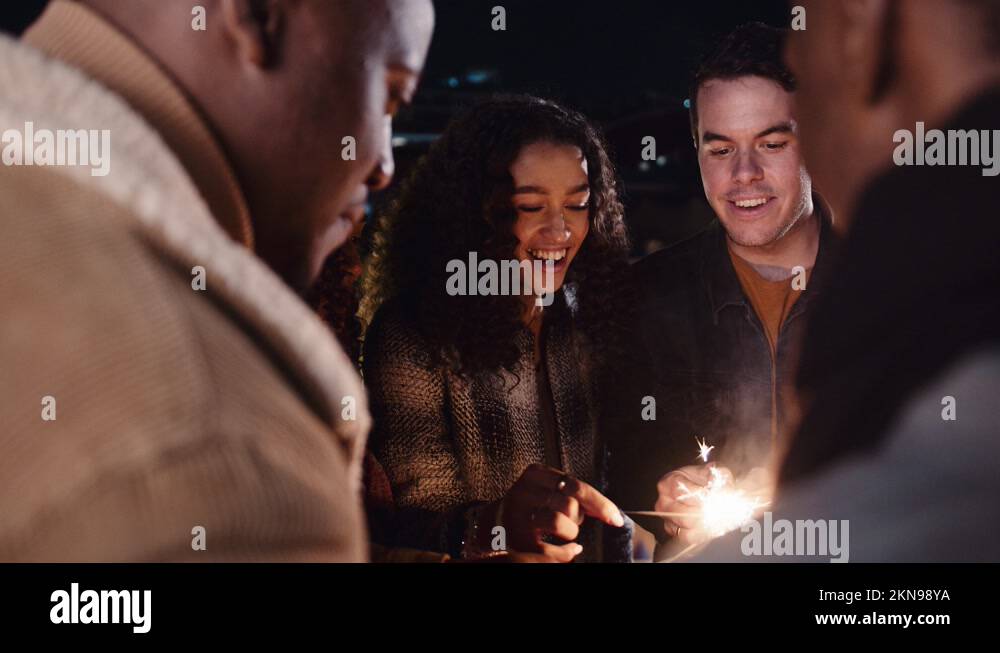 Diverse group of friends lighting their sparklers and dancing outdoors ...