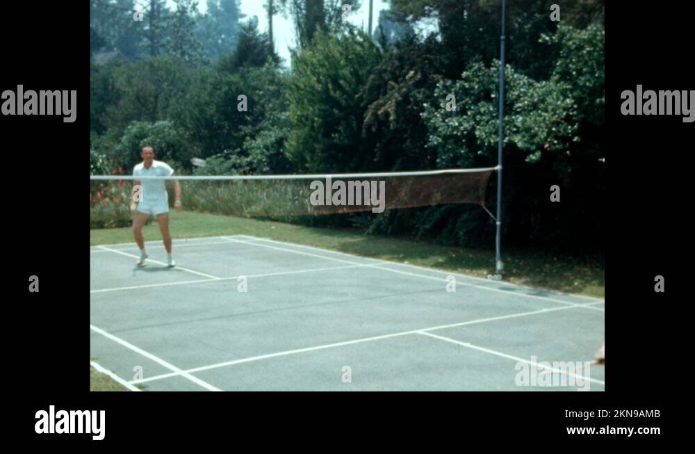 1950s: Two men return shuttlecock during a rally on a badminton court ...