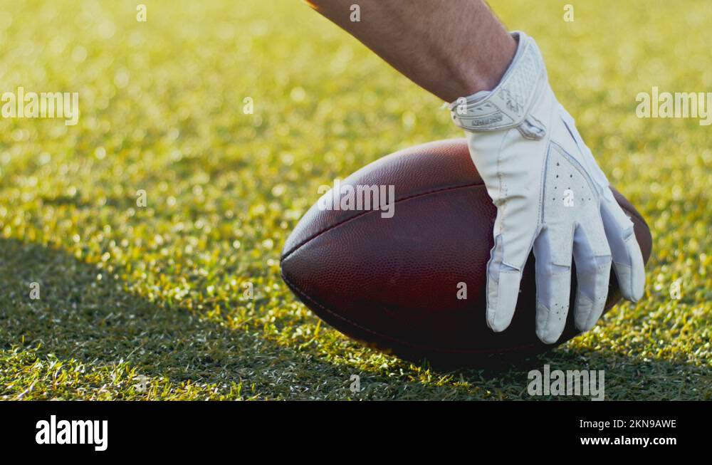 Cropped view of the american football player wearing gloves taking ball ...