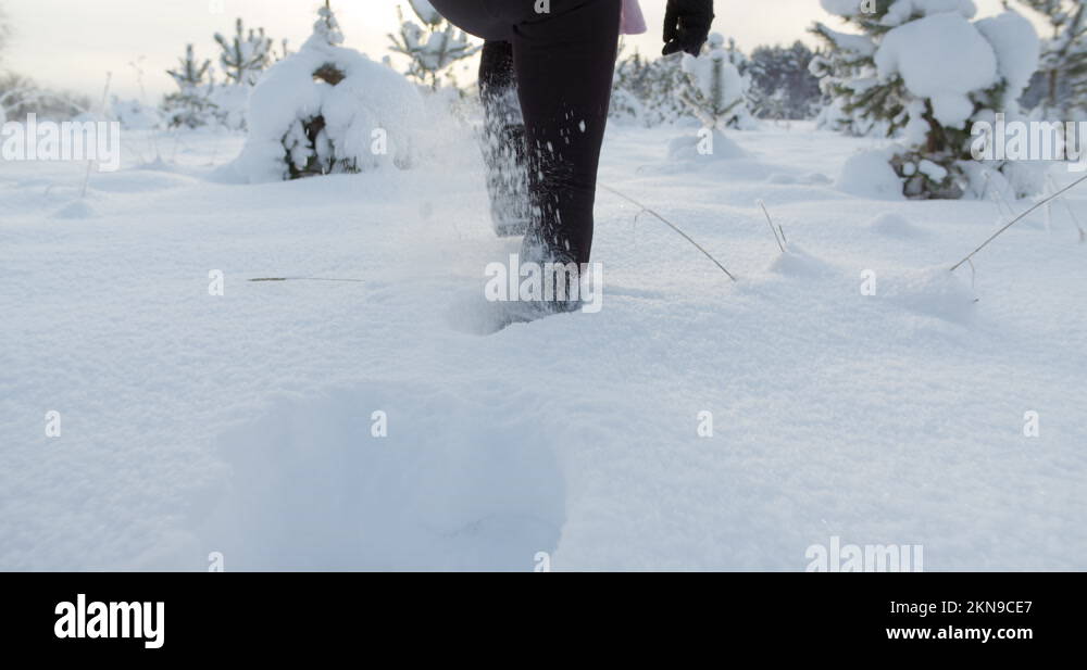 Woman walking in deep snow on sunny winter day close up slow motion ...