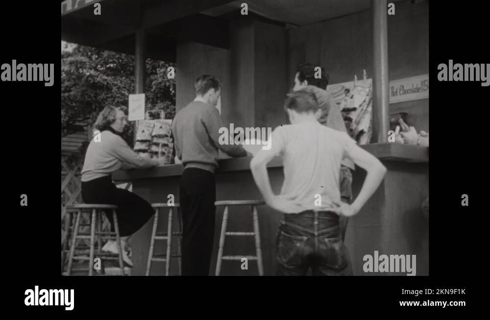 1950s: Boys on curb stand and walk to food counter, push boy at counter ...
