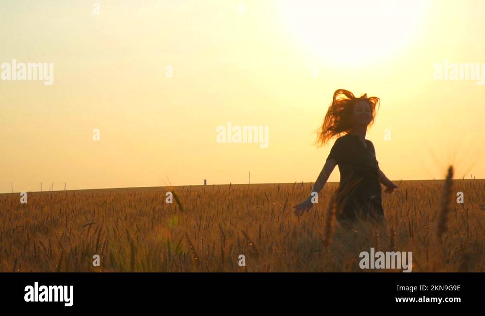 A woman runs across the field at sunset. free spirit of a beautiful ...