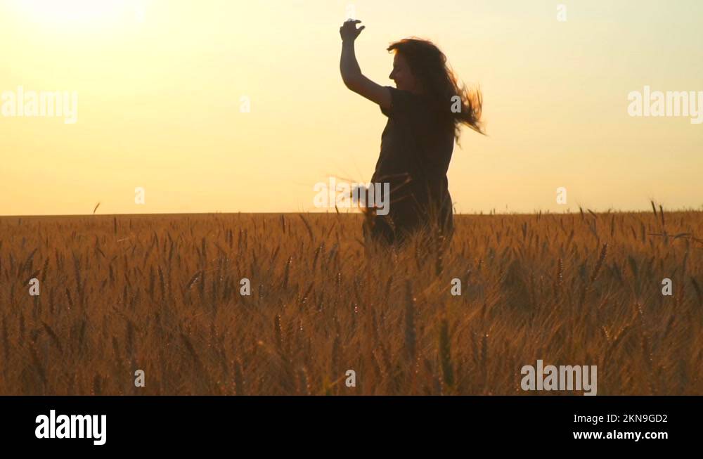A woman runs across the field at sunset. free spirit of a beautiful ...