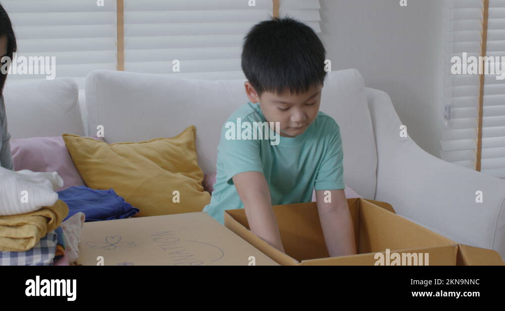 Asian mom and kids prepare donate old clothes packing box at home Stock ...