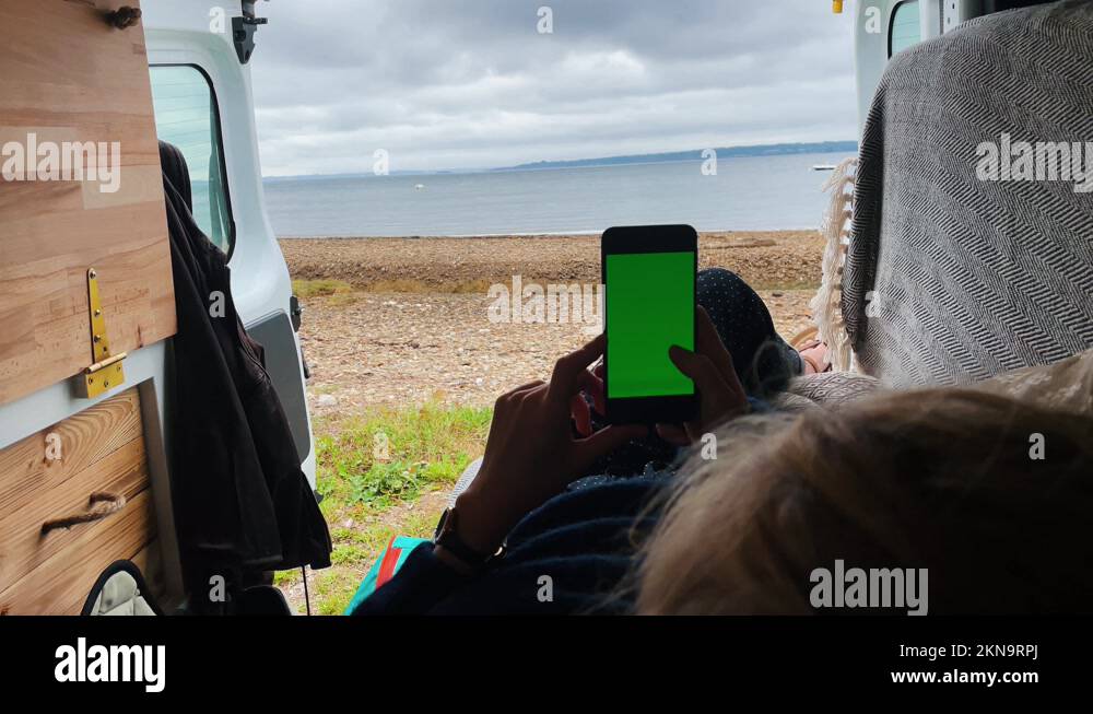 Young Woman use smartphone viewing green screen in camping car on ...