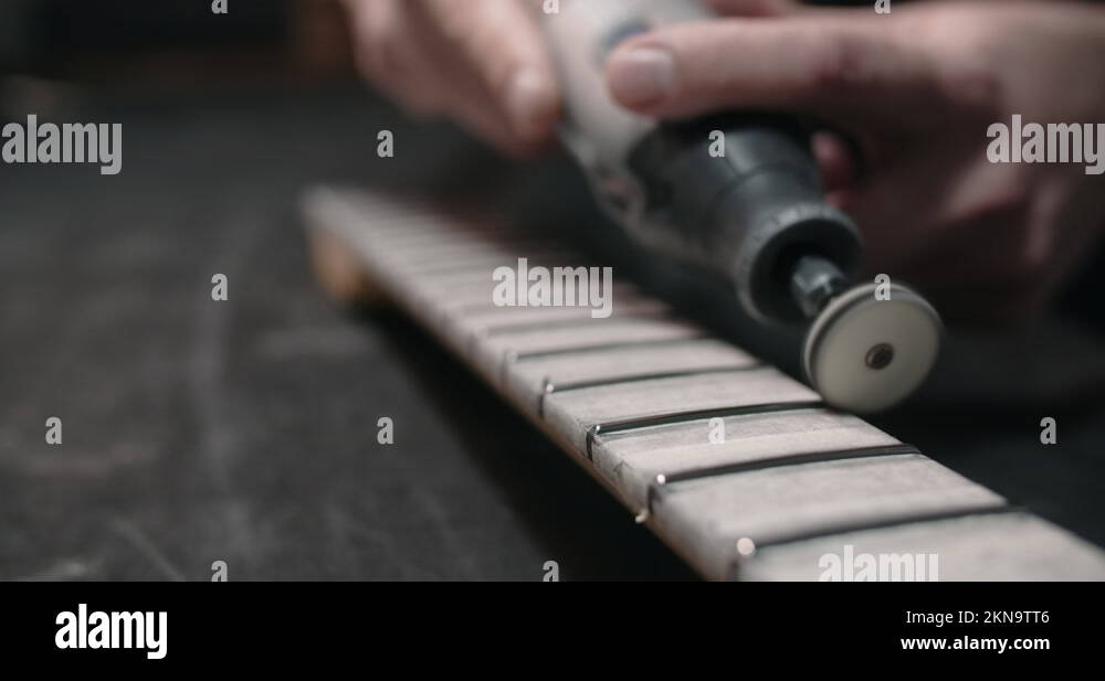 Luthier polishes new frets on the guitar fretboard at musical ...