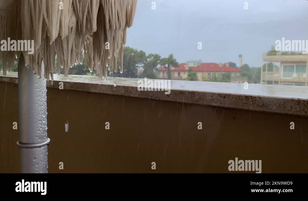 Raindrops fall on the parapet and folded parasol on the balcony Stock Video Footage - Alamy