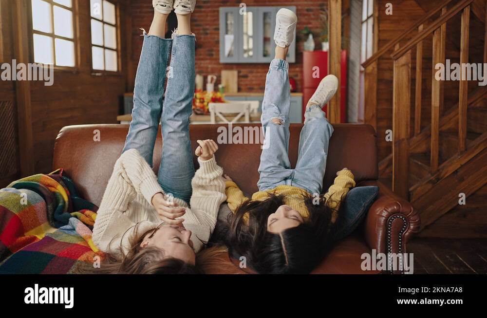 Mother and little daughter falling down on couch with their feet up ...