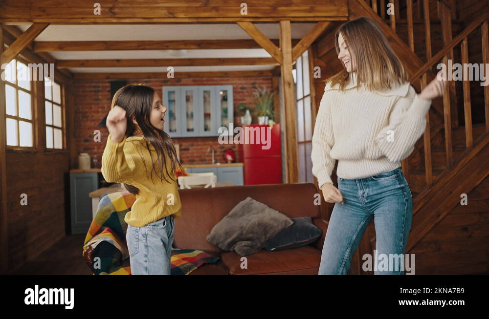 Young mom and little daughter laughing, dancing, falling down on sofa ...