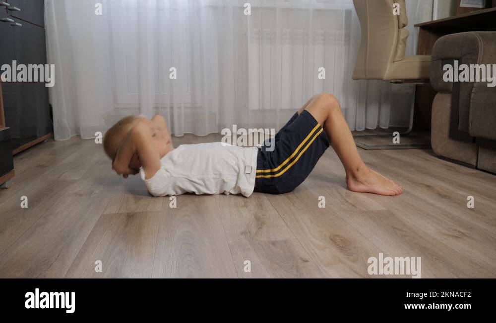 A little eight-year-old boy shakes his abs at home on the floor Stock Video Footage - Alamy