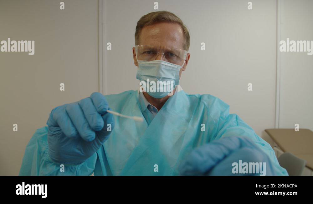 Male healthcare worker in PPE taking patient swab sample for PCR test ...