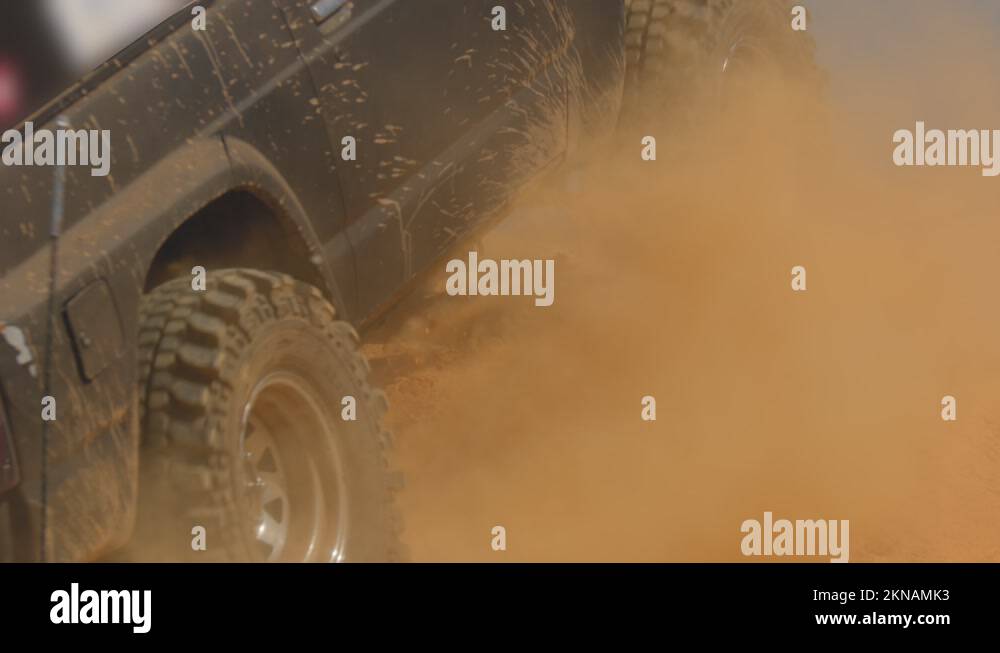 Slow Motion Close Up: Suv driving on sandy road, covered in dust, side ...