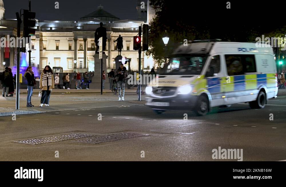 Police vans with blue flashing lights speed through traffic at ...