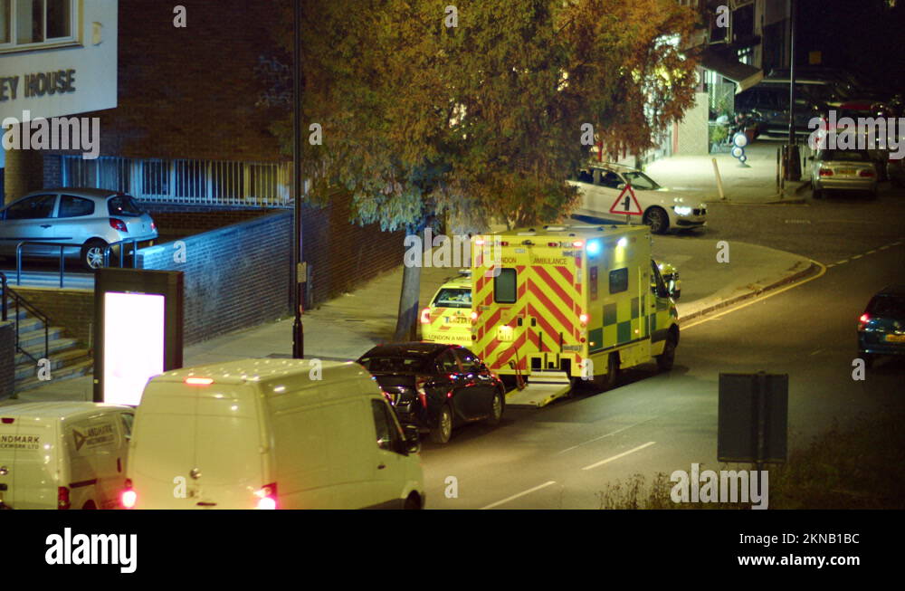 London ambulance with flashing lights parked on a street at night in ...