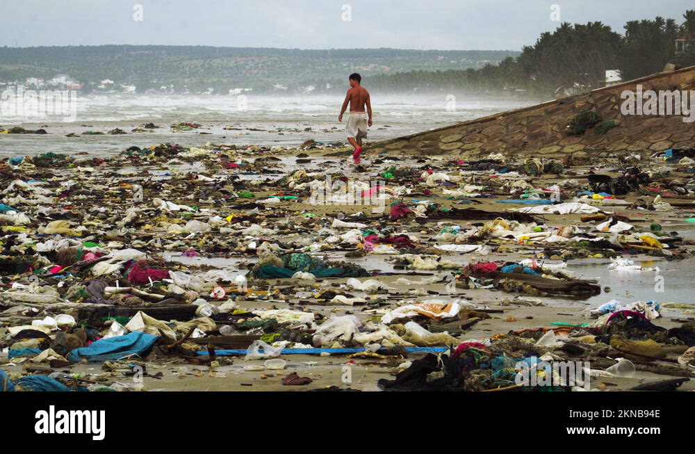 Topless man walking on dirty polluted beach full of trash on a gloomy ...
