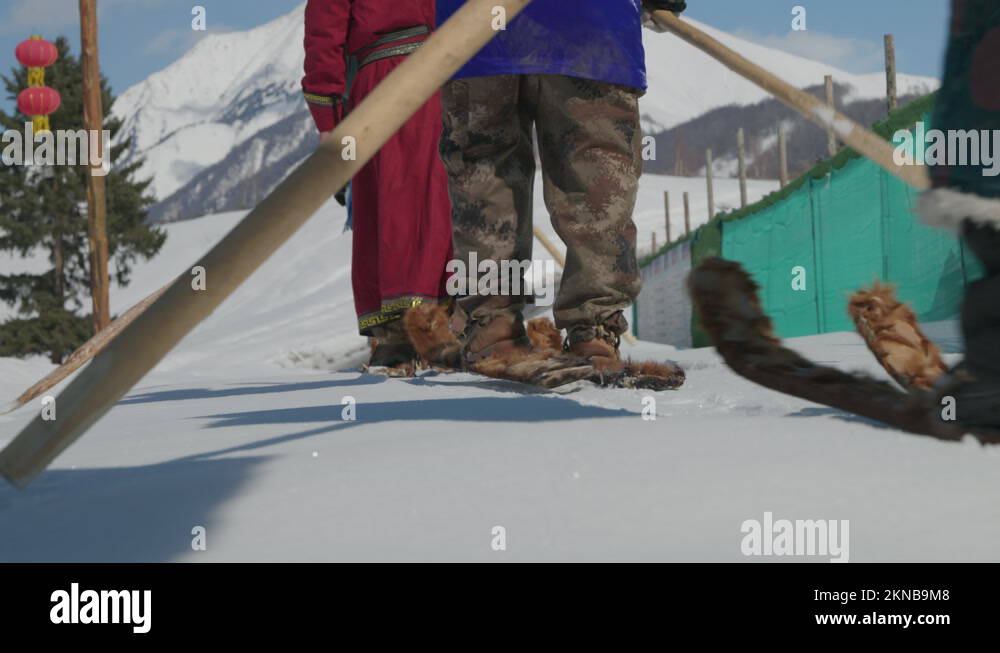 Men dressed in traditional deel walking in ancient fur ski in snow ...