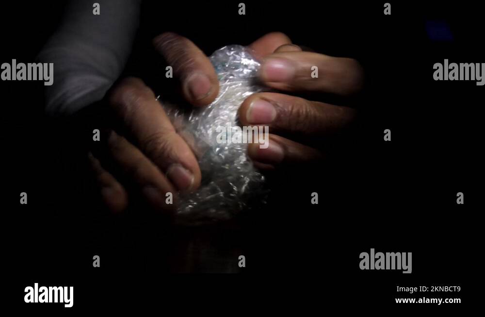 hand holding globe trapped in a plastic bag with black background stock ...