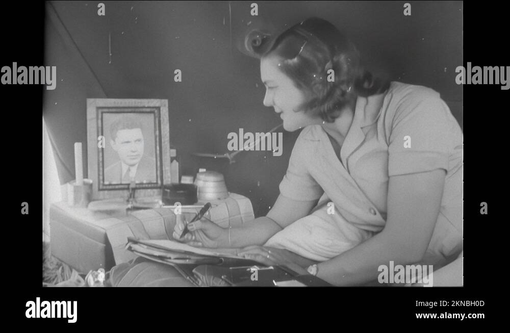 1940s: Woman in tent writing letter, looks at photo of man. Men hanging ...