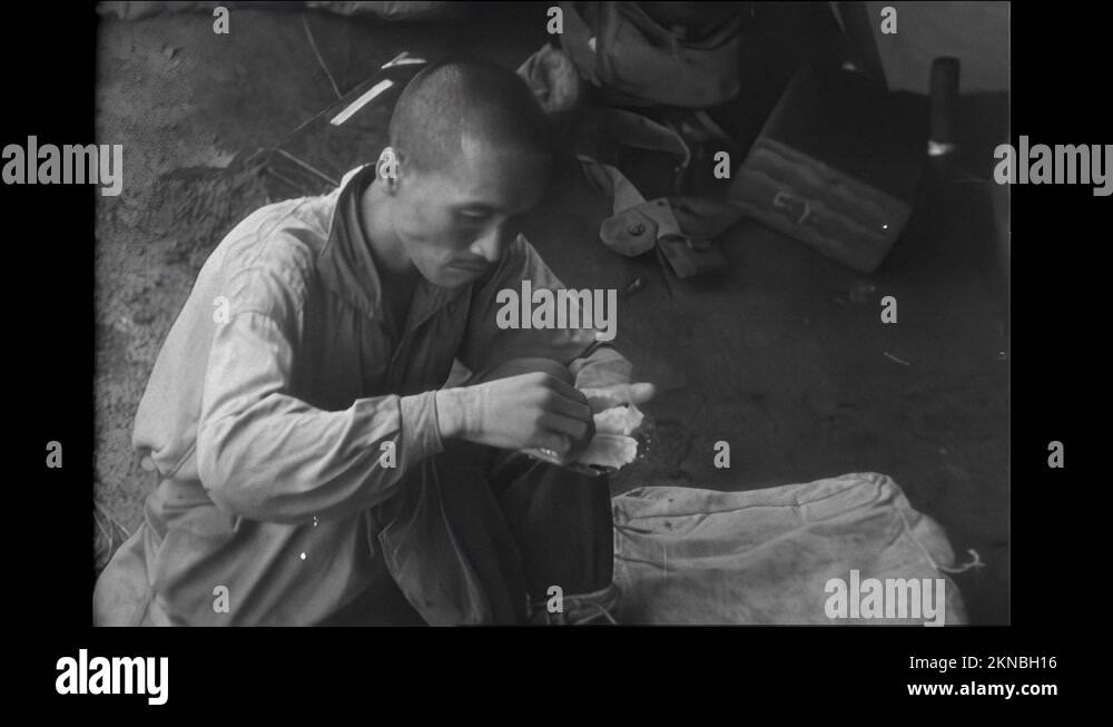 1940s: Man sitting on the ground, eating. Man sitting, calmly looking ...