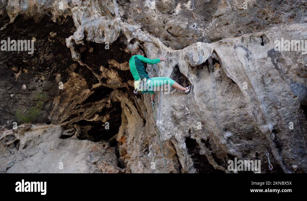 strong female rock climber trying to climb hard tough rock route on ...