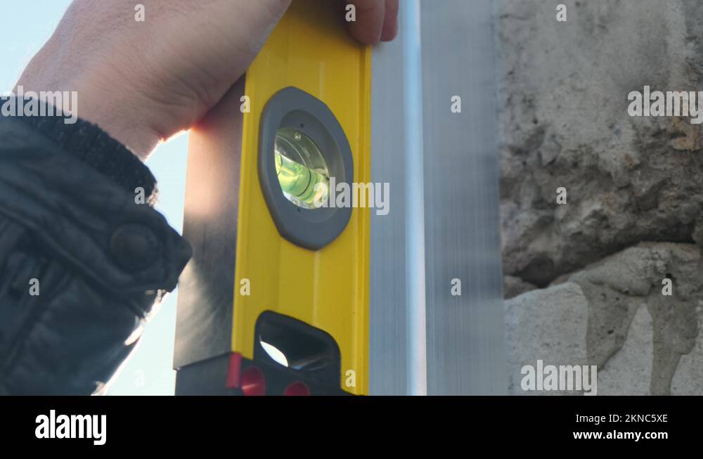 Close-up. Builder's hands using a spirit level inspecting the ...