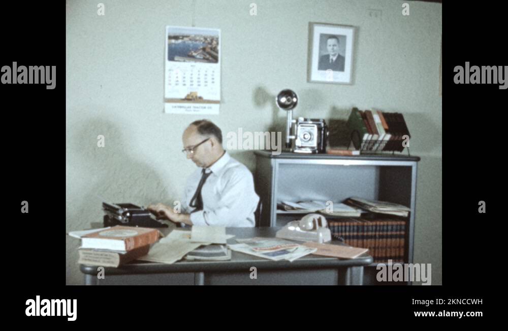 1950s: Man in suit at desk takes notes and types on typewriter. Second ...