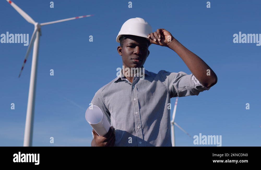 African American electrical engineer in a helmet and with a drawing in ...