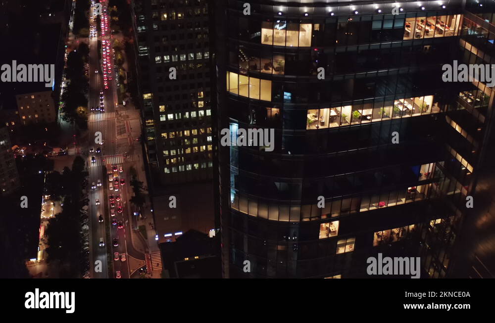 Modern high rise office building with glossy facade reflecting lights ...
