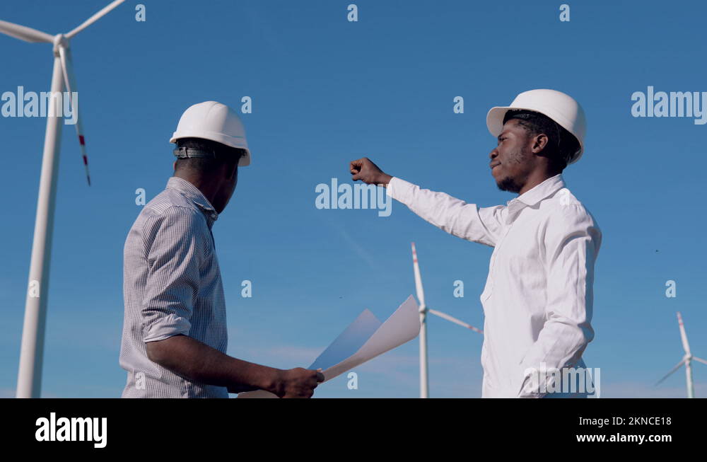 Two male African American electrical engineers stand in the background ...