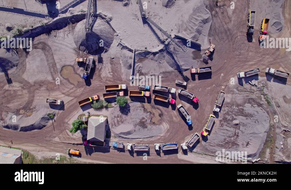 Excavators and tractors load crushed stone and rock into dump trucks ...