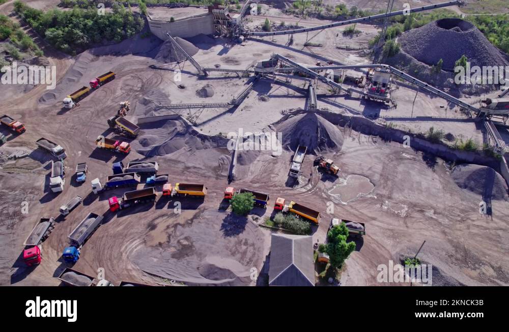 Excavators and tractors load crushed stone and rock into dump trucks ...