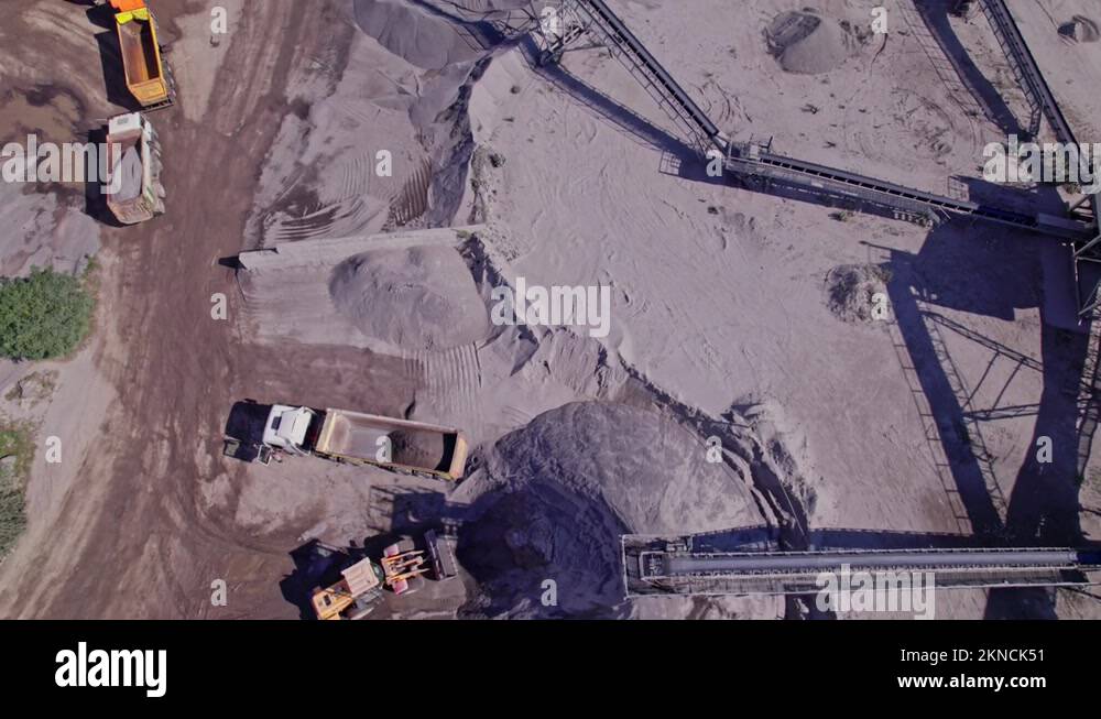 Excavators and tractors load crushed stone and rock into dump trucks ...