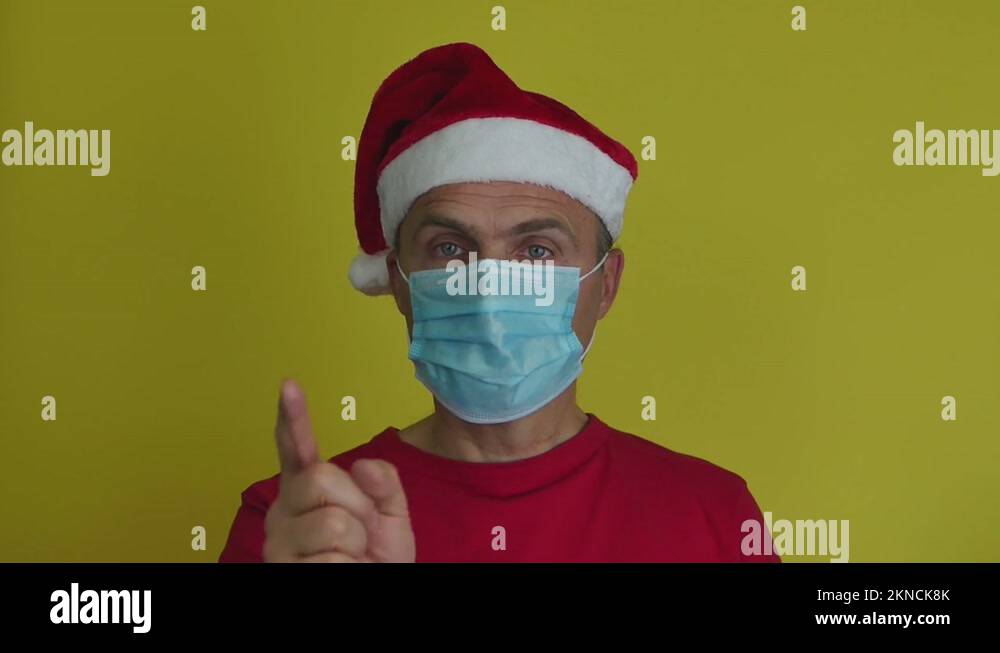 A man in a Santa hat and a mask refuses and prohibits with a gesture ...