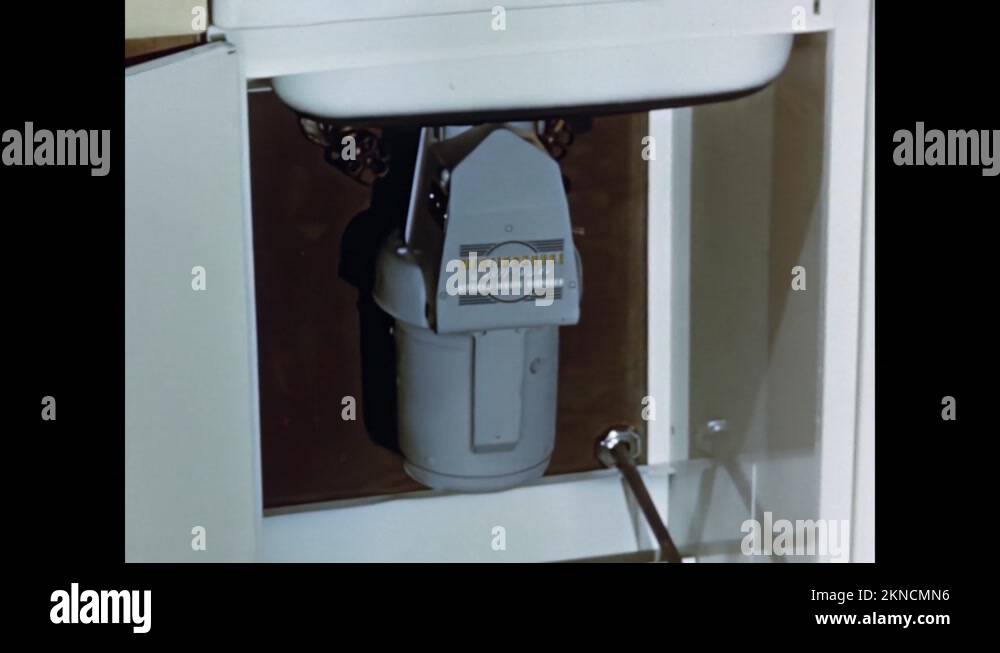 1950s: Garbage disposal hangs next to dishwasher. Salesman smiles and ...