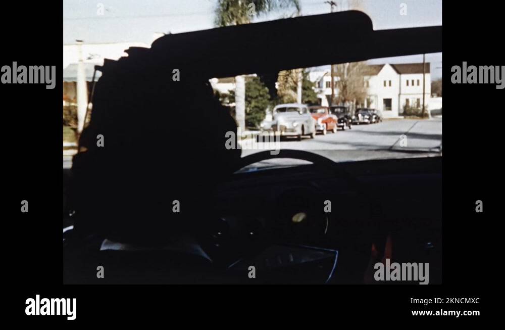 1950s: Woman drives convertible along city streets. Discolored car ...