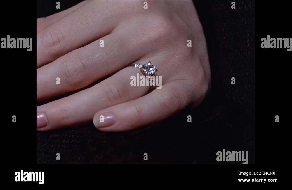 1960s: Teenage boy and girl walk arm in arm down sidewalk at night ...