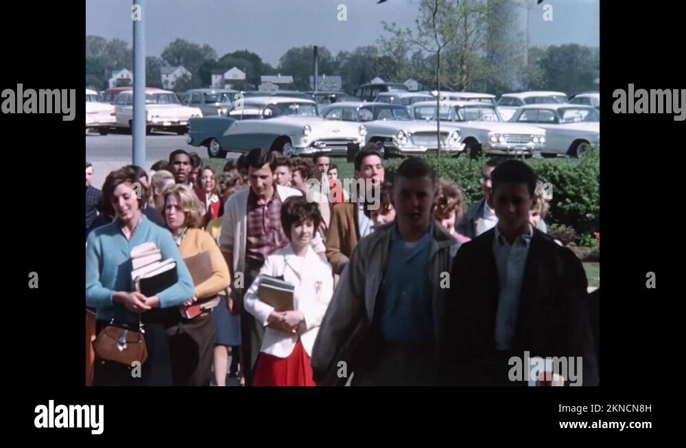 1960s: Students walk from parking lot to school building. Teenage girl ...