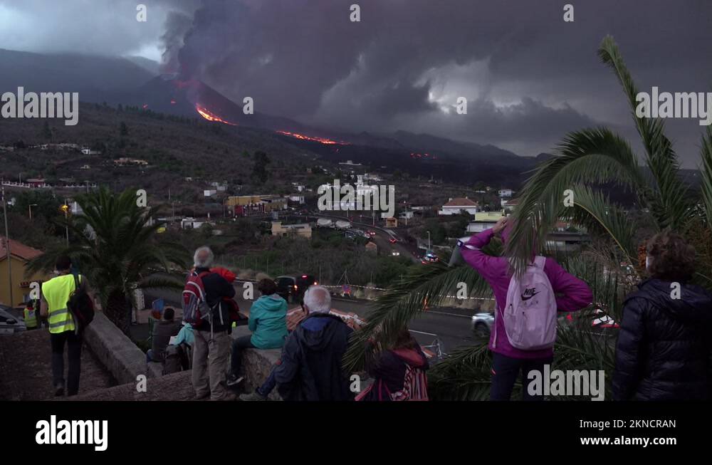 People stand watching the Cubre Vieja volcano eruption as a new lava ...