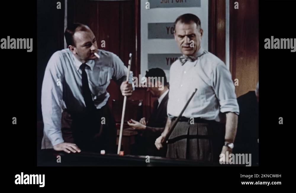 1950s: Men talk and play billiards at pool hall. Cue strikes ball. Pool ...