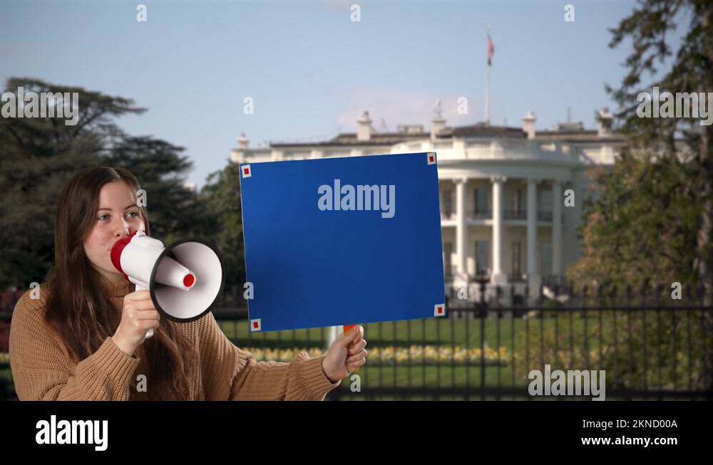 A woman holds a blank green screen sign and talks into megaphone for ...