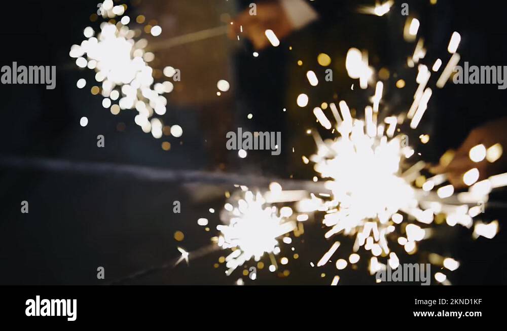 Evening sparklers are lit in the hands of people at the event. Close-up ...